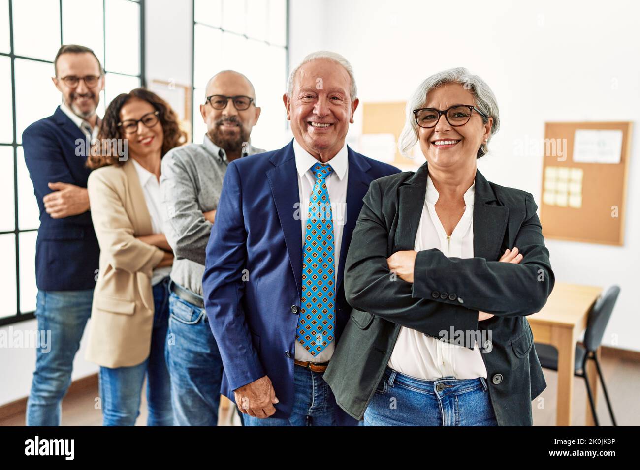 Group of middle age business workers smiling happy standing with arms ...