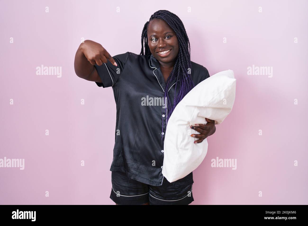 Young african woman wearing pijama hugging pillow looking confident ...