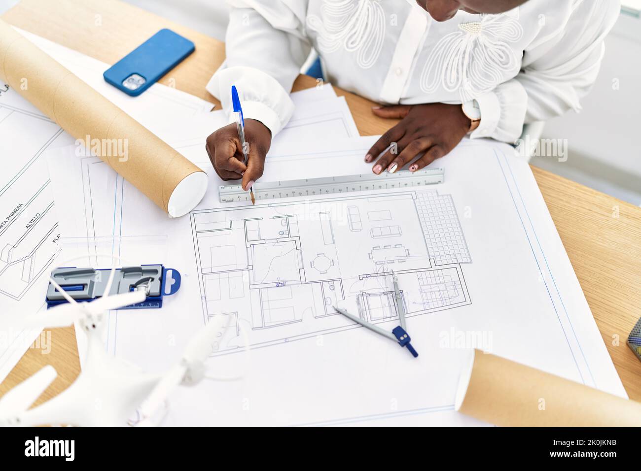 Young african american woman architect drawing on house plans at ...