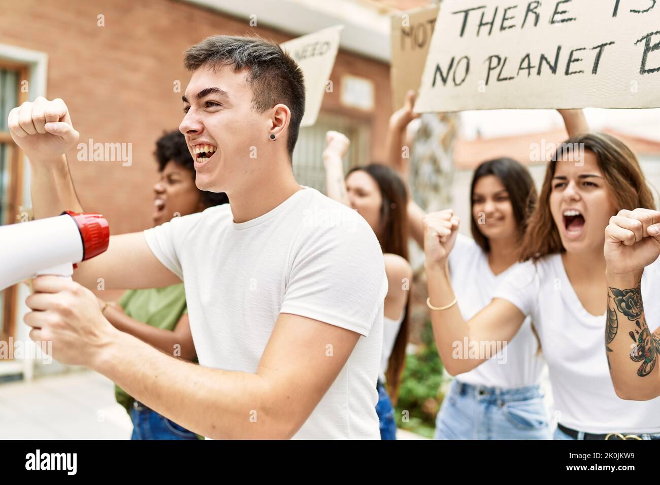 Group of young activists people protesting holding banner and using ...