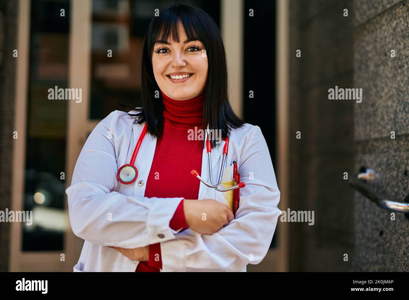 Young brunette woman wearing doctor uniform and stethoscope at house ...
