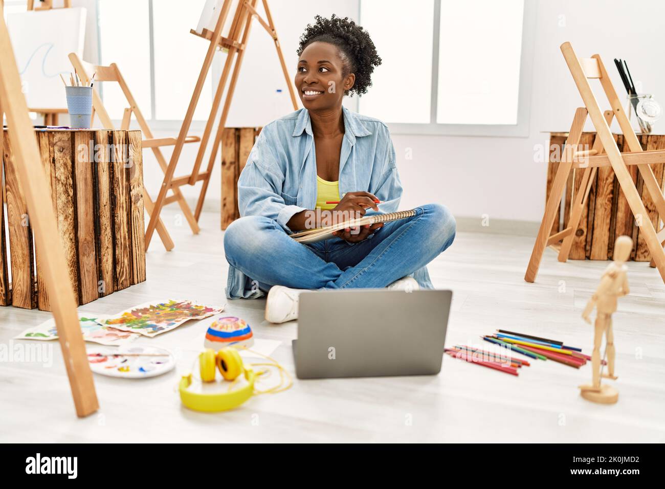 Young african american artist woman using laptop drawing at art studio ...