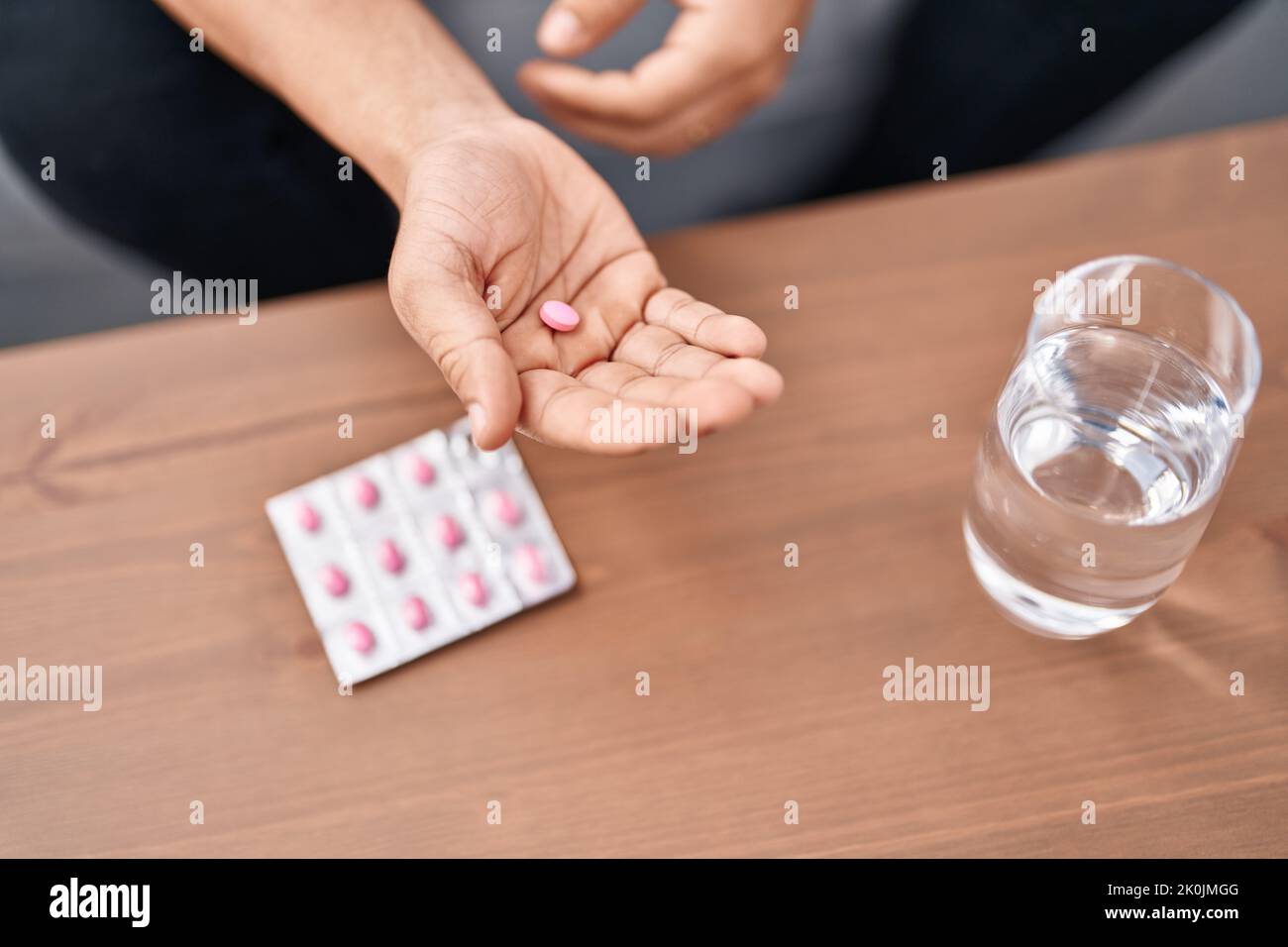 African american man taking pills sitting on sofa at home Stock Photo ...