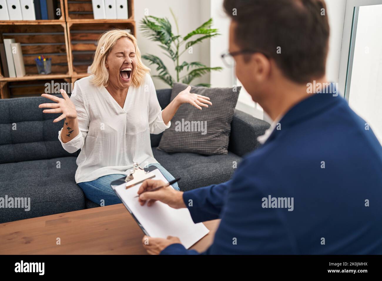 Middle age woman at psychology therapy office celebrating mad and crazy ...