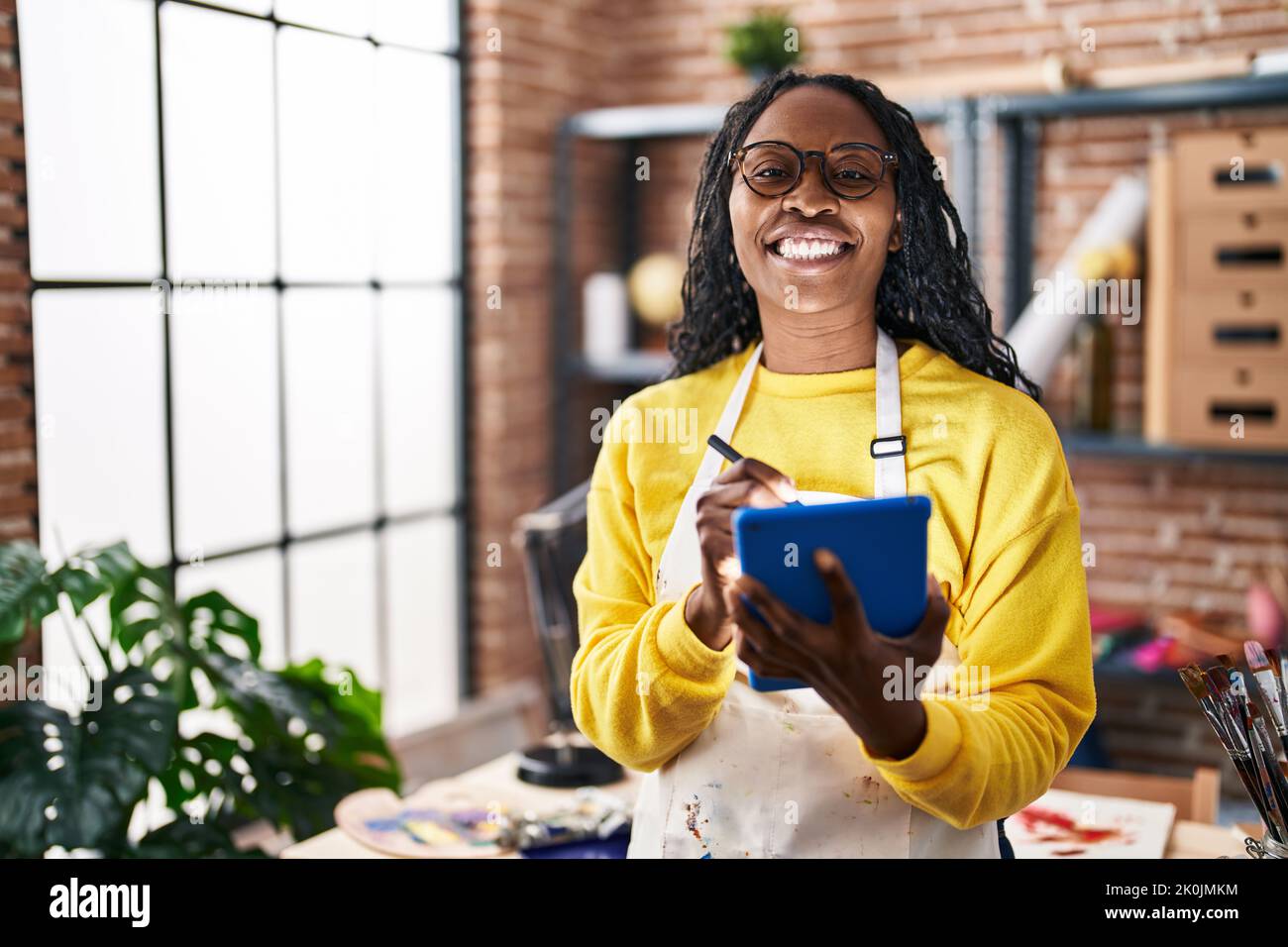 African american woman artist smiling confident using touchpad at art ...