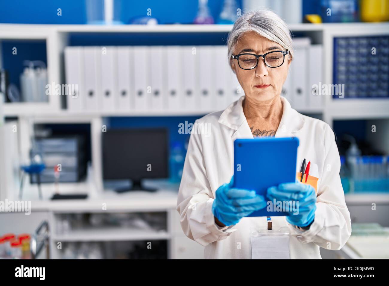 Middle age grey-haired woman scientist using touchpad working at laboratory Stock Photo - Alamy