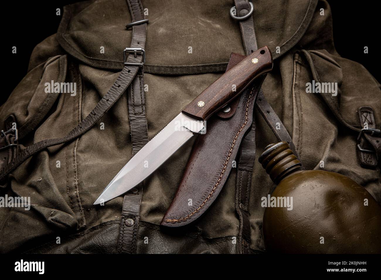 A hunting knife with a wooden handle and a leather sheath on a khaki ...