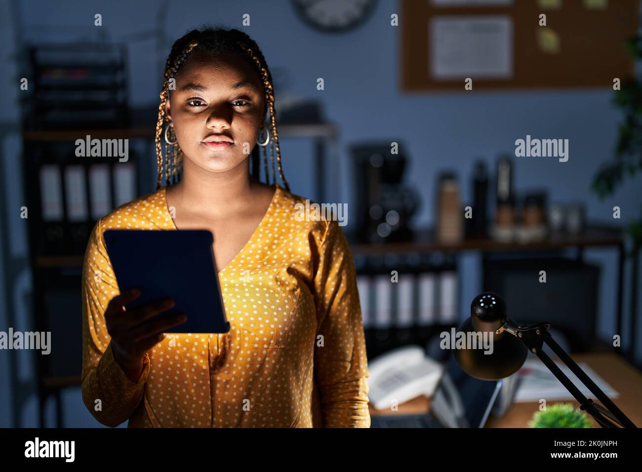 African american woman with braids working at the office at night with ...
