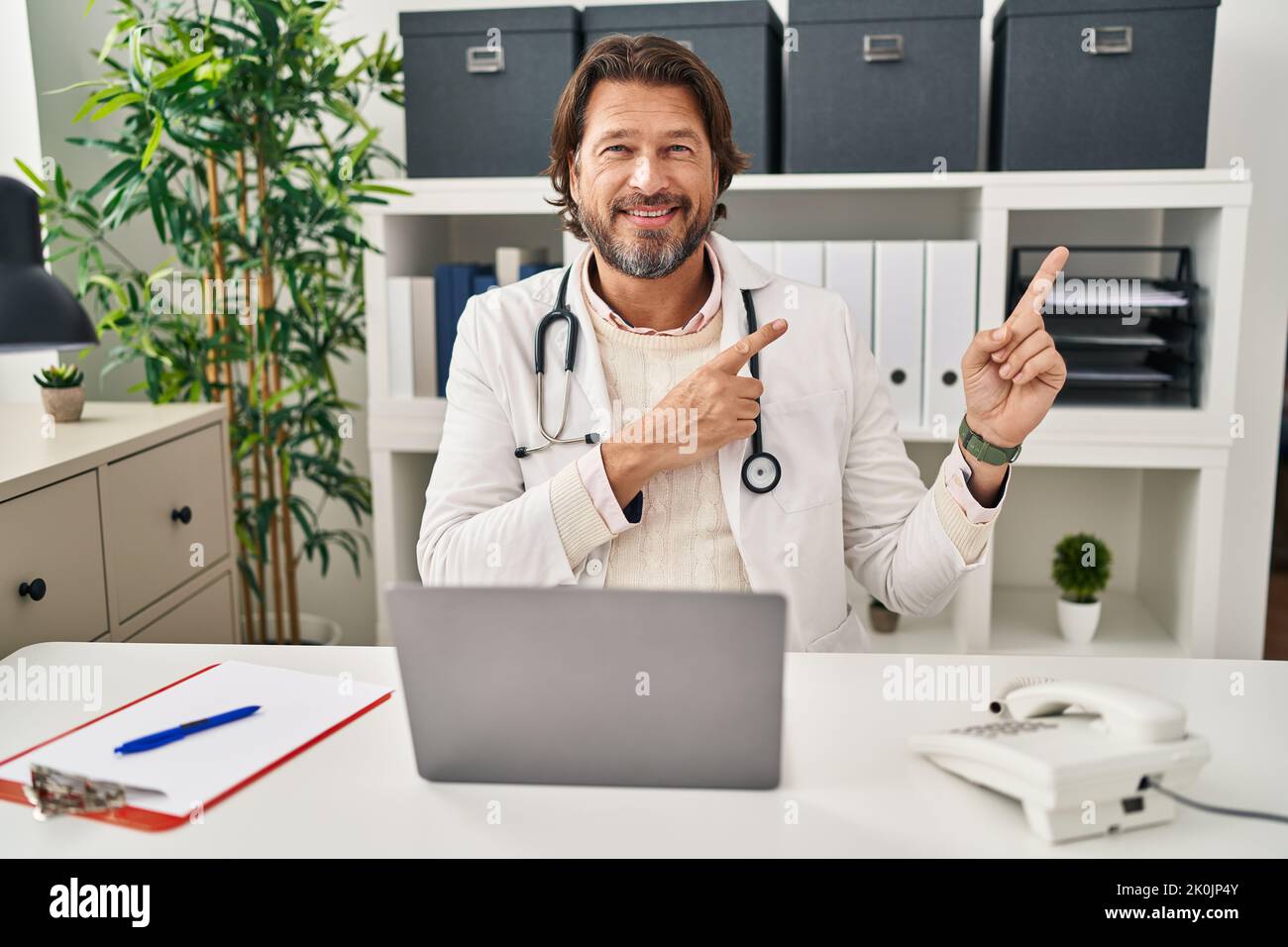 Handsome middle age doctor man working at the clinic smiling and ...
