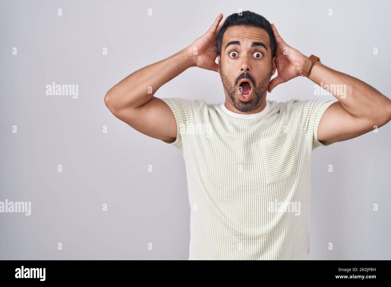 Hispanic man with beard standing over isolated background crazy and ...