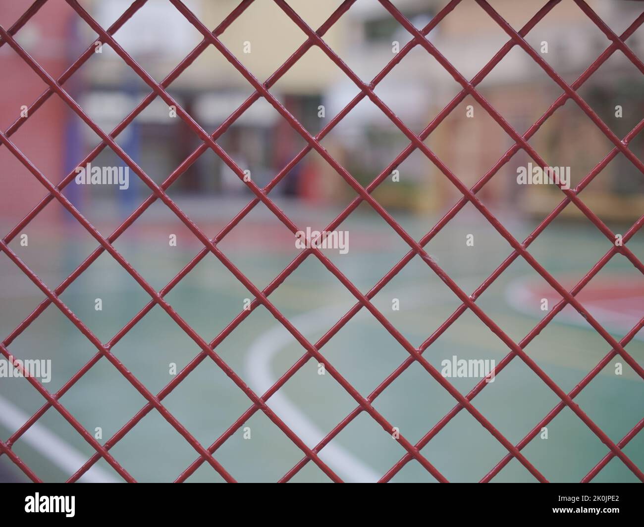 A red reticulated fence of a basketball stadium with blurred background ...