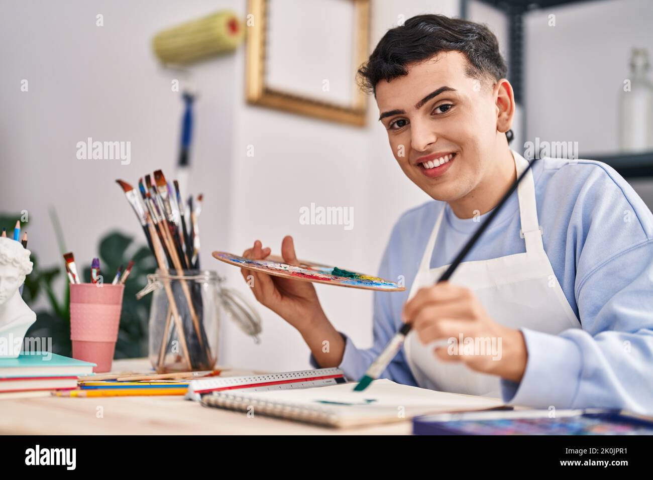 Young non binary man artist smiling confident drawing on notebook at ...