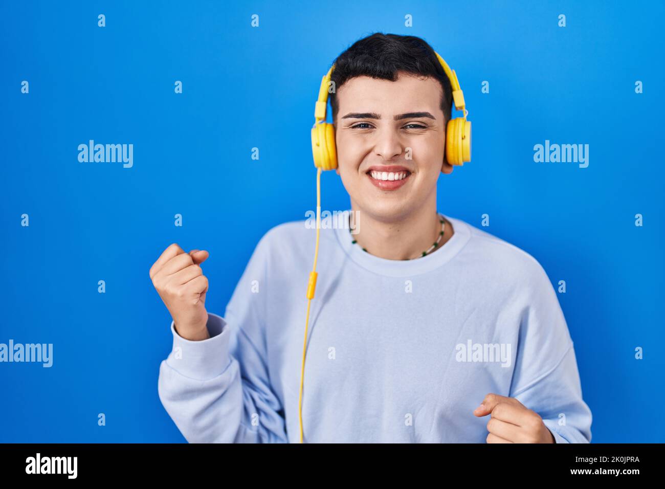 Non binary person listening to music using headphones very happy and ...