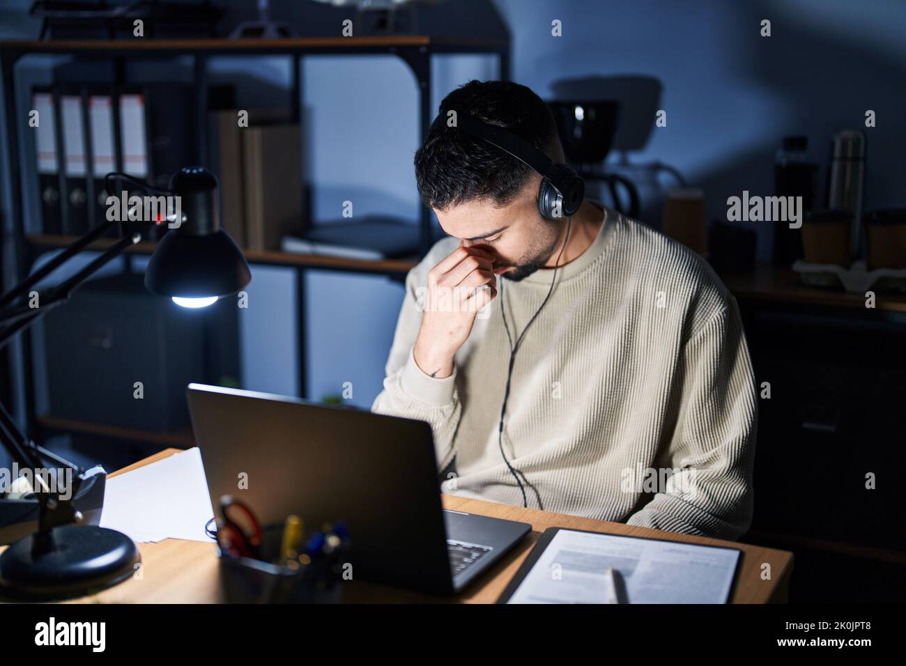 Young handsome man working using computer laptop at night tired rubbing ...