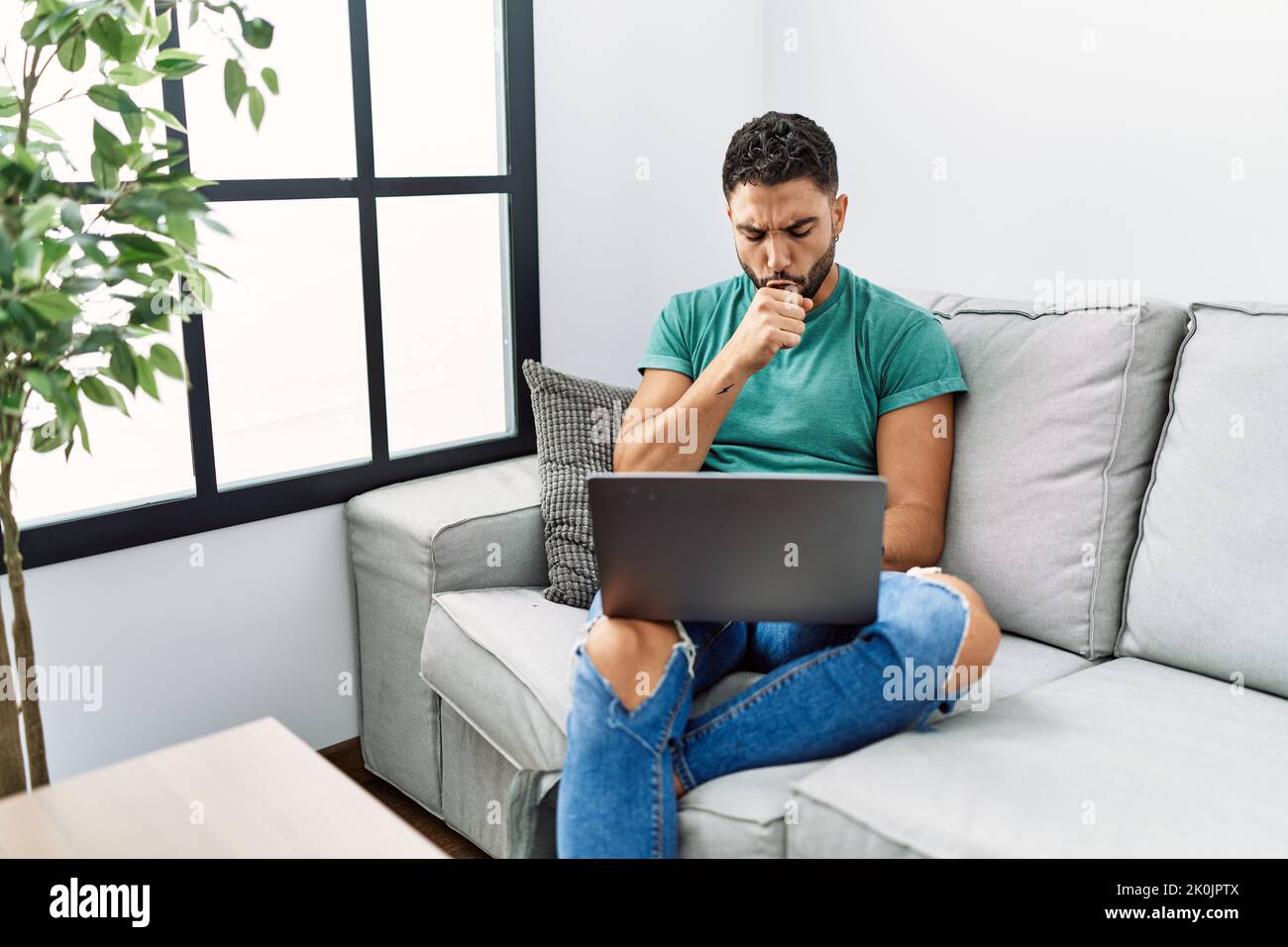Young handsome man with beard using computer laptop sitting on the sofa ...