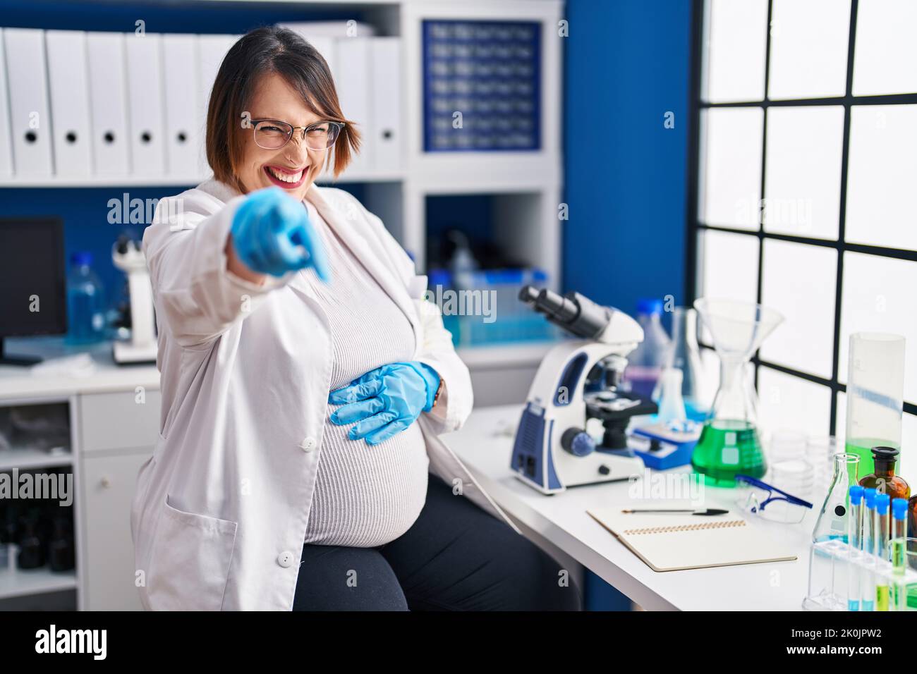 Pregnant woman working at scientist laboratory pointing displeased and ...