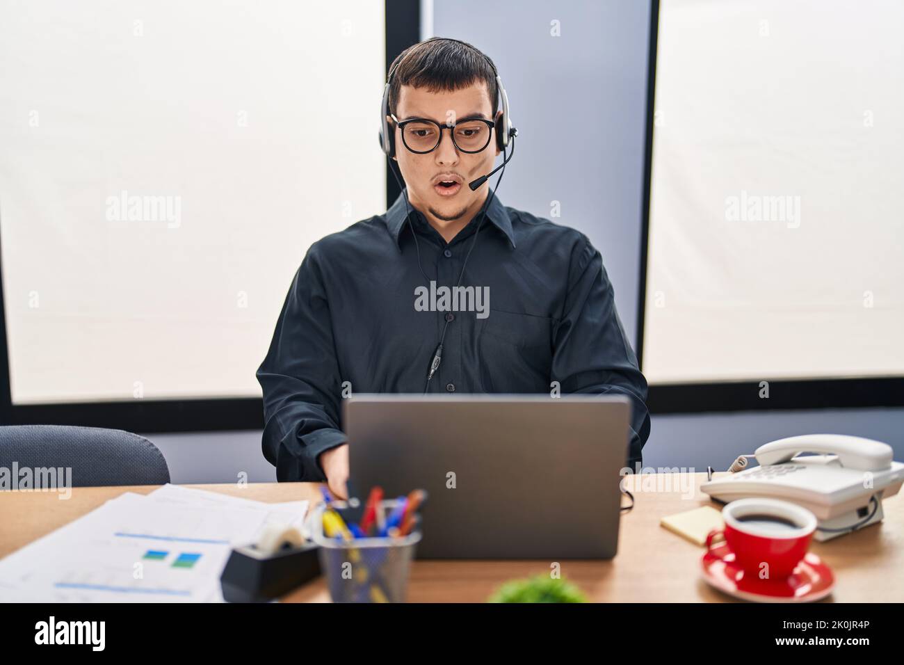 Young arab man wearing call center agent headset scared and amazed with ...