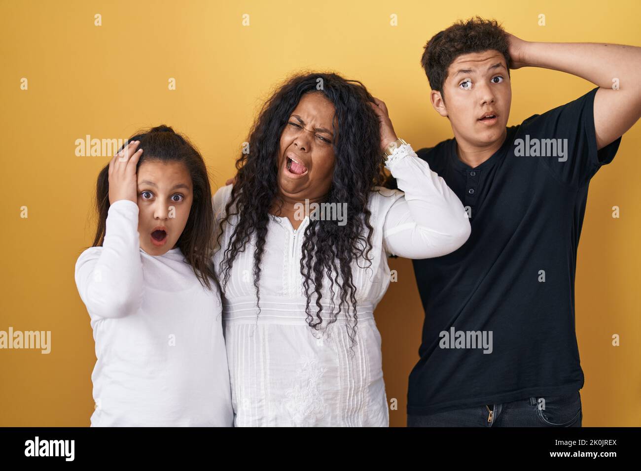 Family of mother, daughter and son standing over yellow background ...