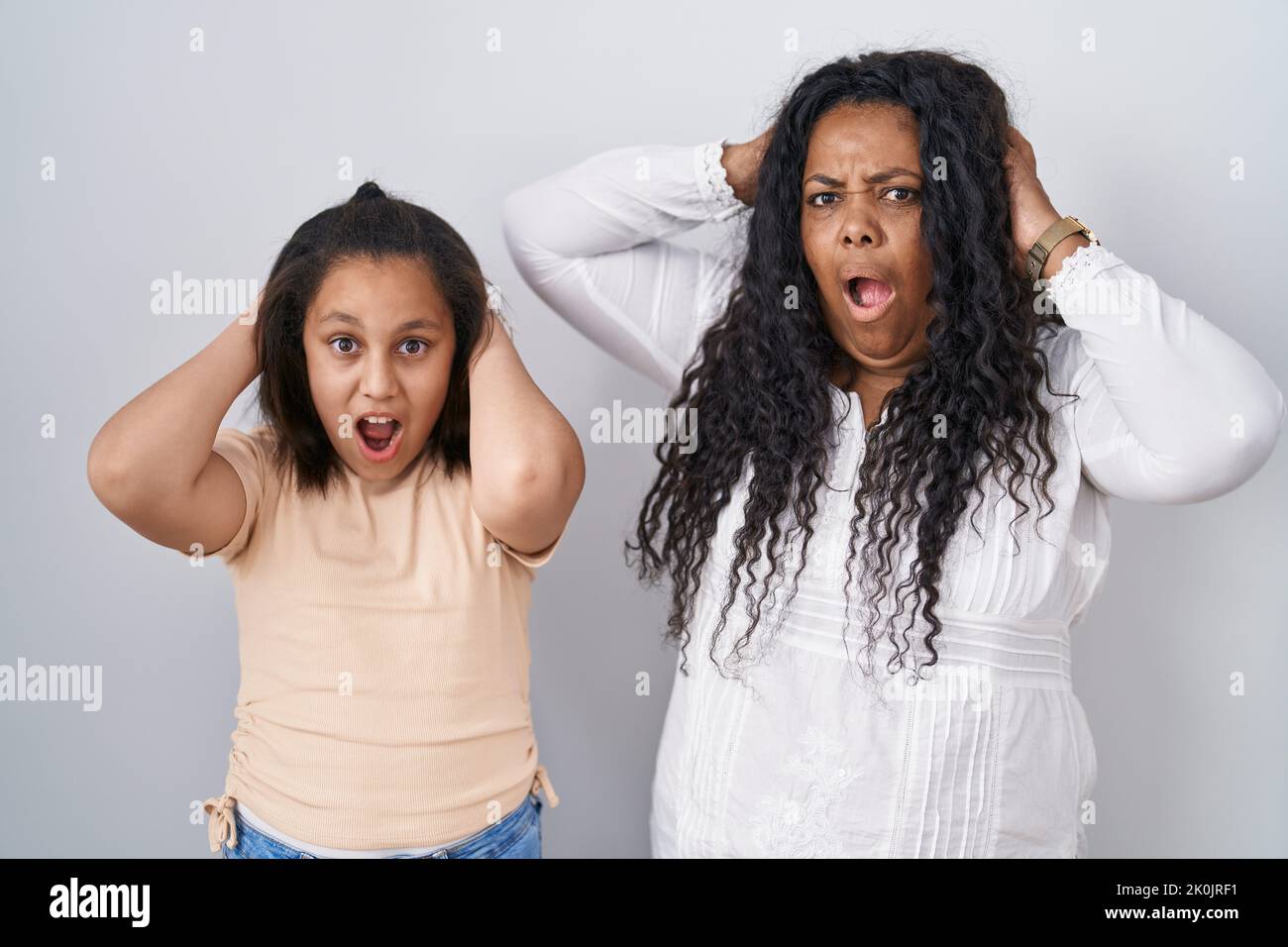Mother and young daughter standing over white background crazy and ...