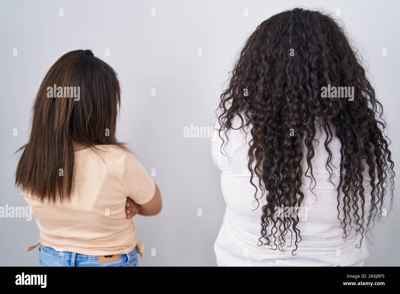 Mother and young daughter standing over white background standing ...
