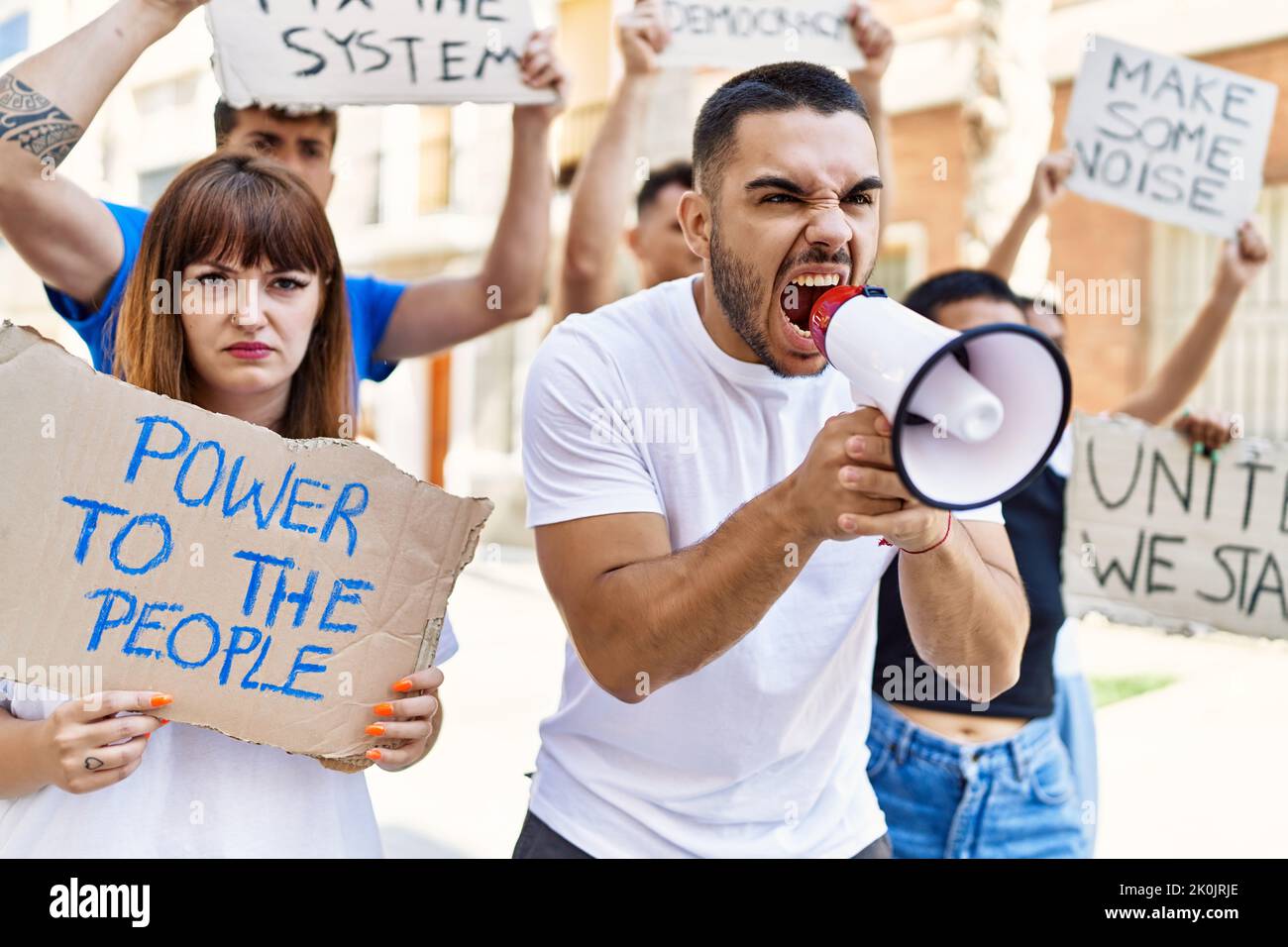 Group of young activists protesting holding banner and using megaphone ...