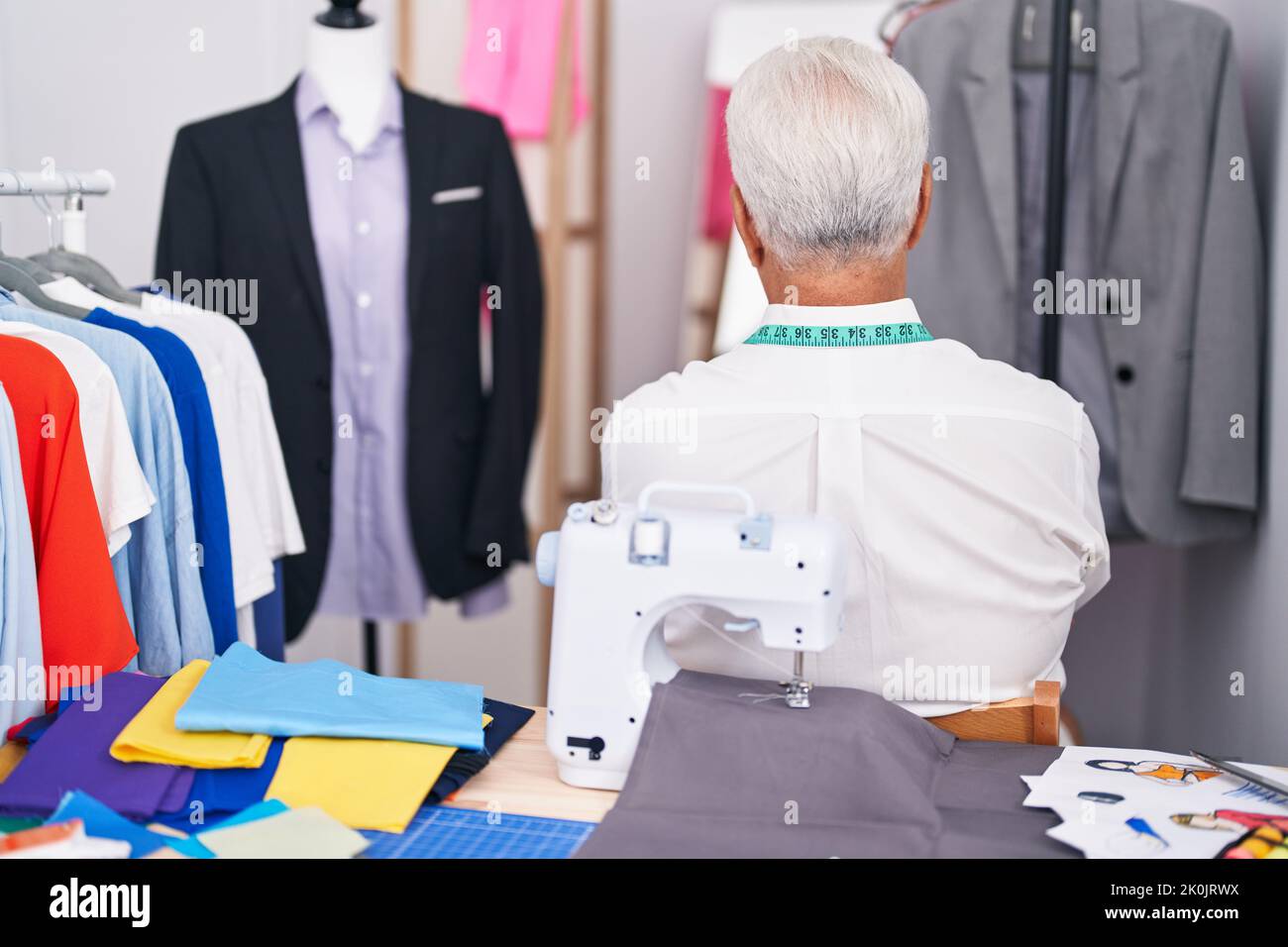 Middle age man with grey hair dressmaker using sewing machine standing ...