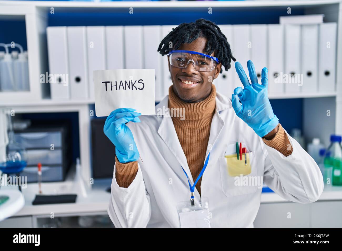 Young african man with dreadlocks working at scientist laboratory doing ...