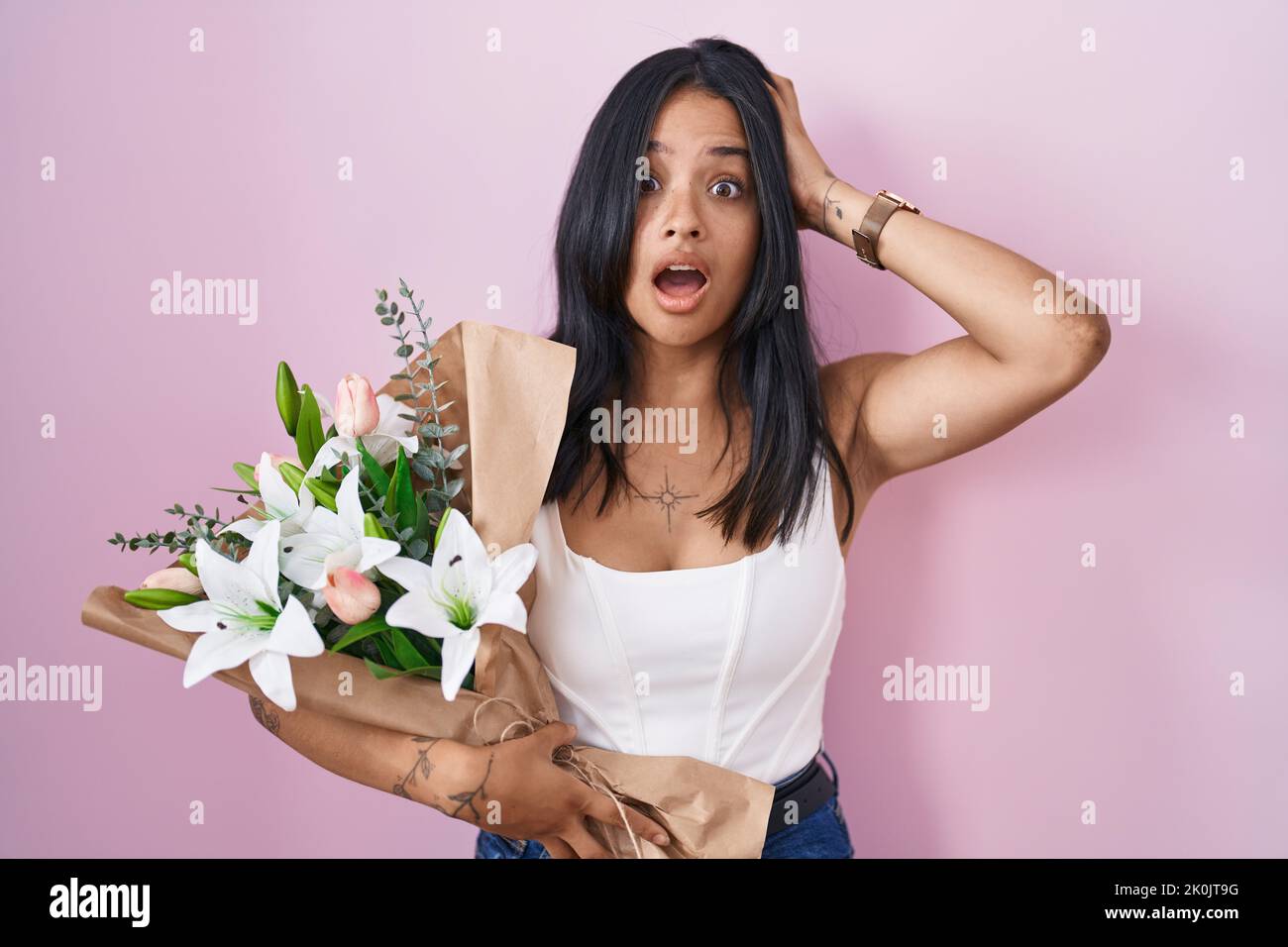 Brunette woman holding bouquet of white flowers crazy and scared with ...