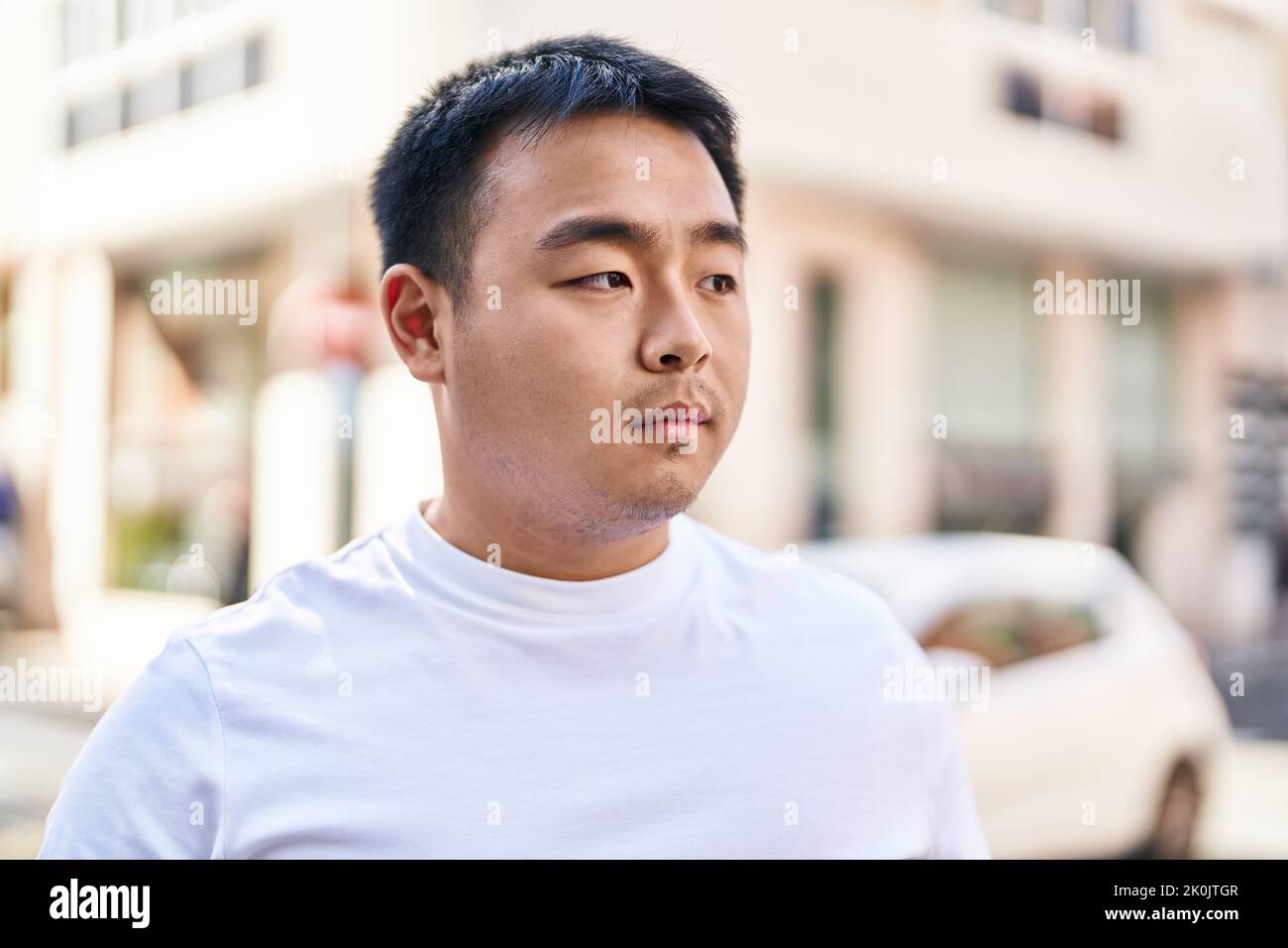 Young chinese man standing with relaxed expression at street Stock ...