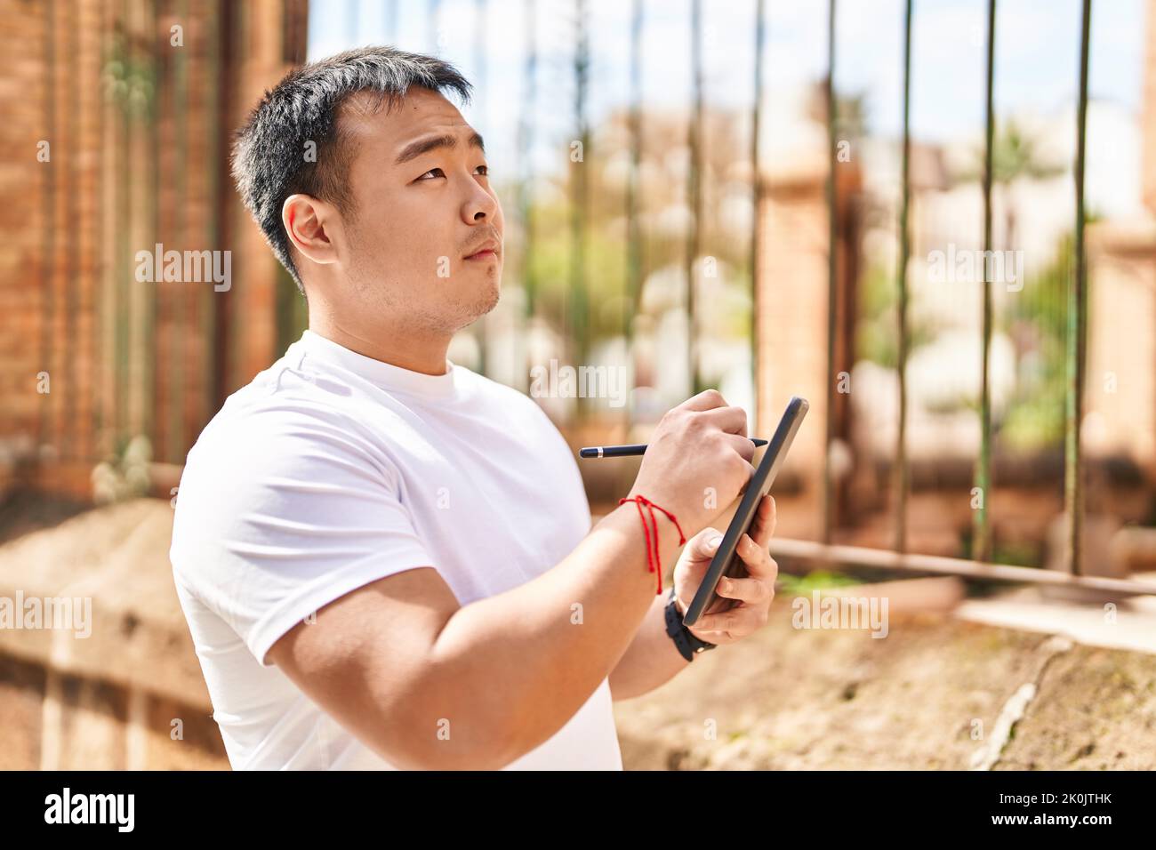 Young chinese man using touchpad at street Stock Photo - Alamy
