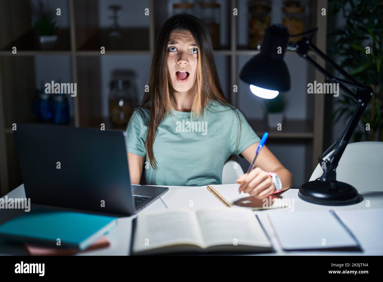 Teenager girl doing homework at home late at night angry and mad ...
