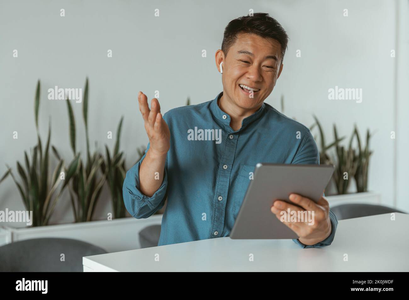 Smiling asian businessman making videocall to client sitting in modern ...