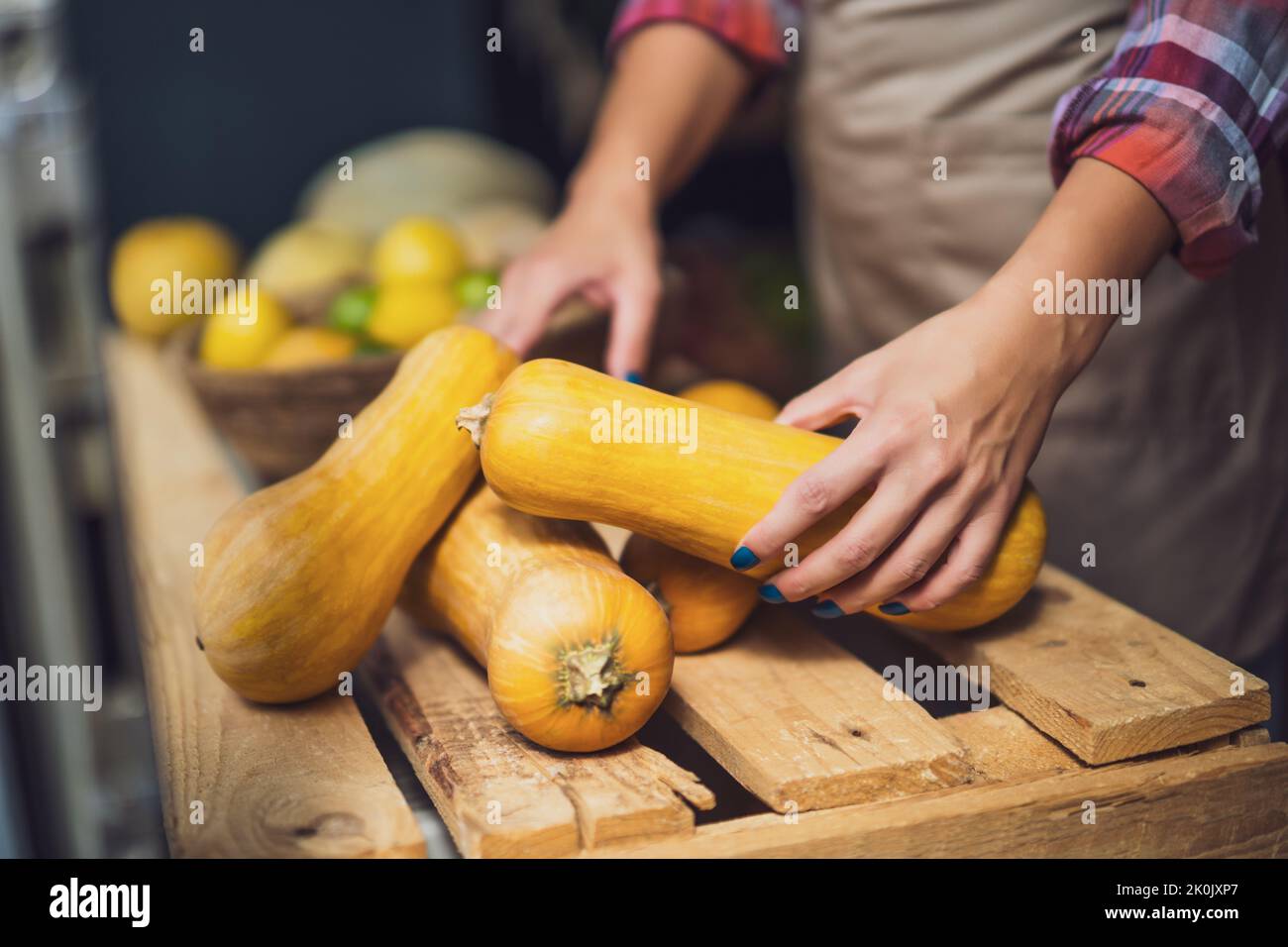 Woman works in fruits and vegetables shop. She is stacking goods in ...