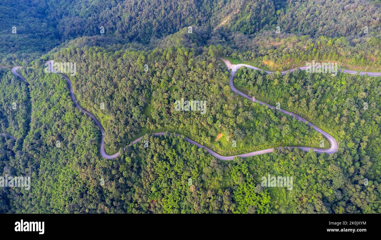 Aerial view of a hilltop road with beautiful green forests in Thailand ...
