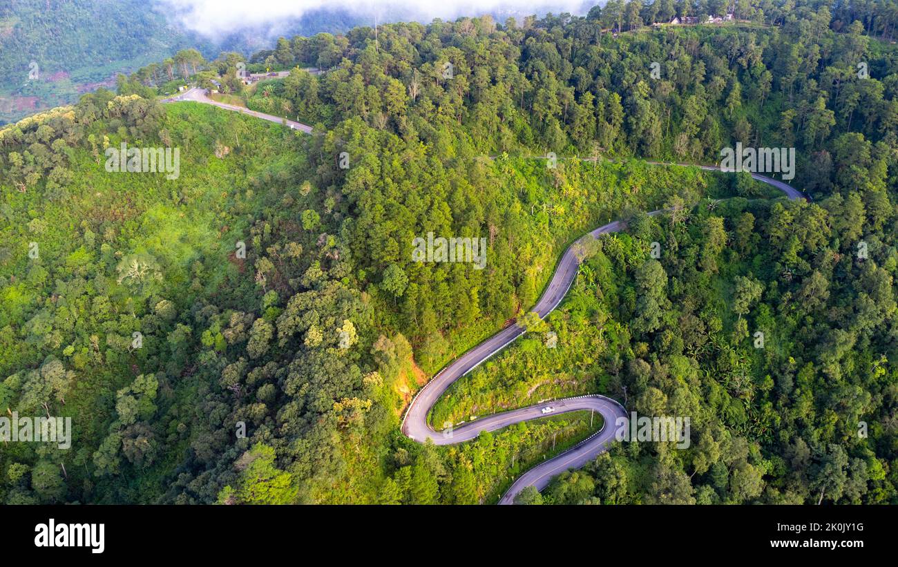 Aerial view of a hilltop road with beautiful green forests in Thailand ...