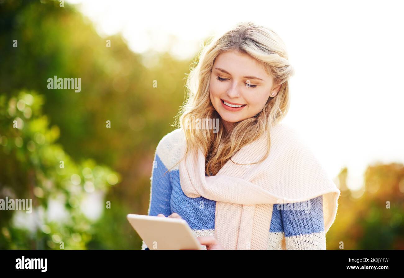 Connected to nature. a young woman using her tablet outdoors Stock ...