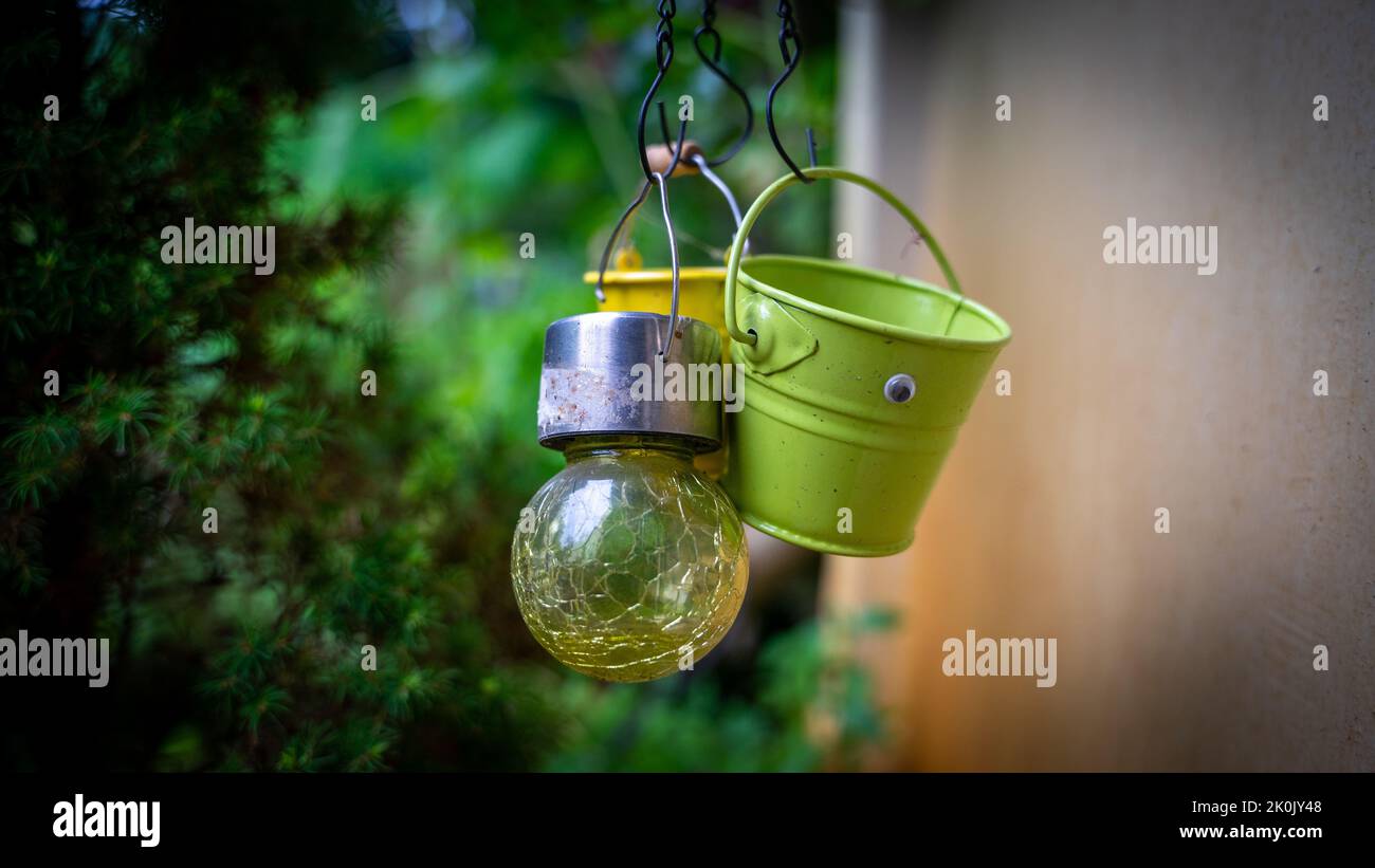 A closeup of small metal buckets with a yellow decorative bulb hanging ...