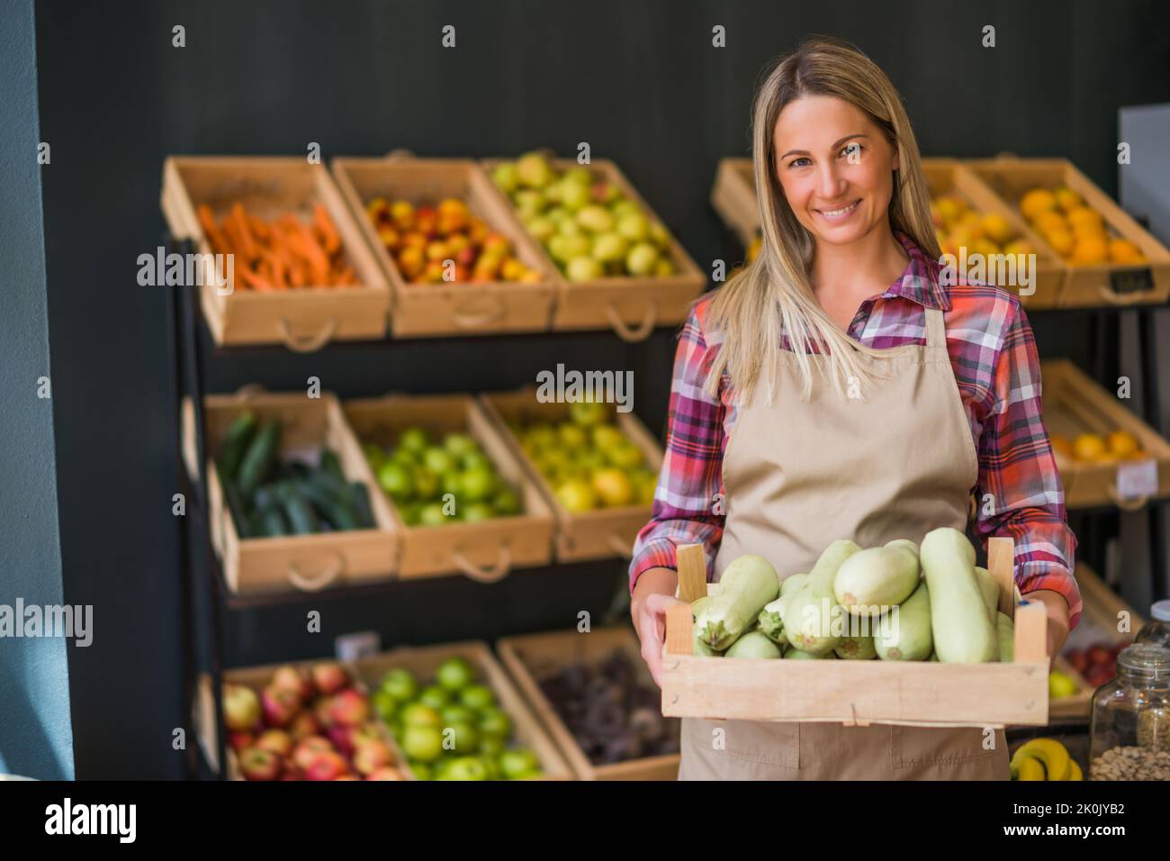 Woman works in fruits and vegetables shop. She is holding basket with ...