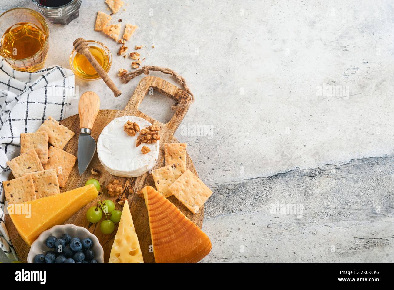 Assortment of cheese, honey, cracker, blueberries, grapes with red and ...