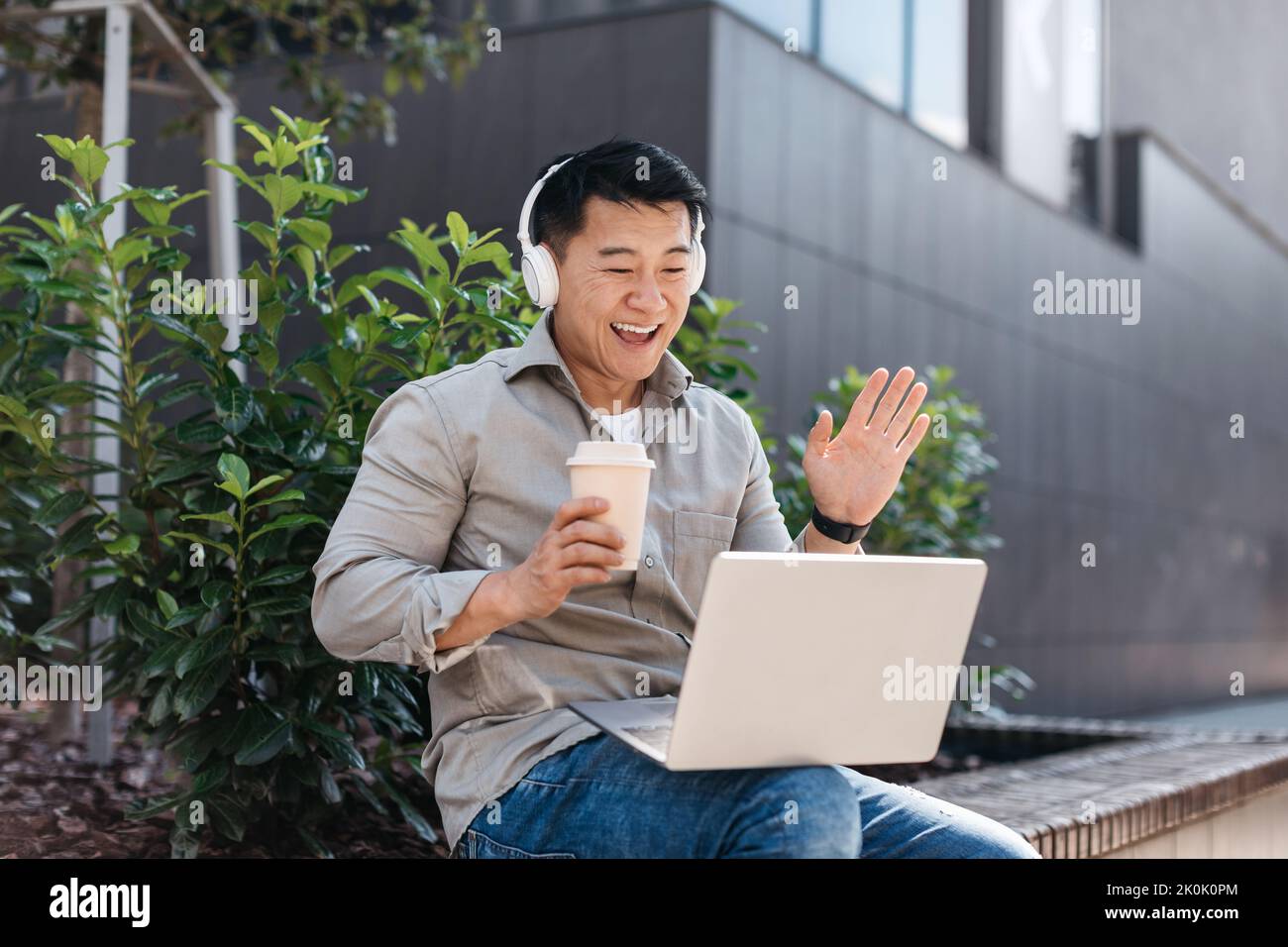 Excited asian middle aged businessman working on laptop outdoors ...