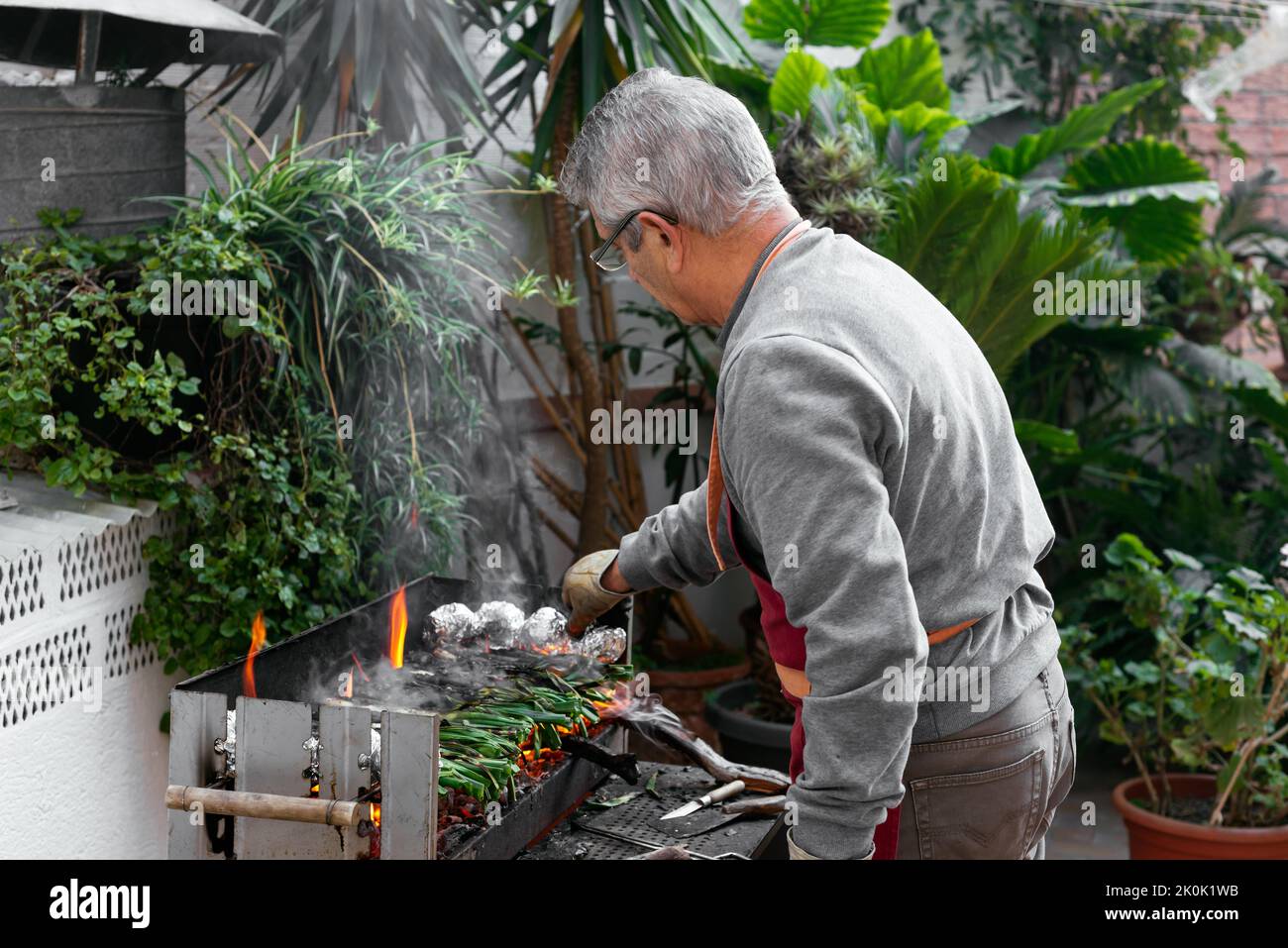 Side view man in protective gloves grilling traditional Catalonian ...