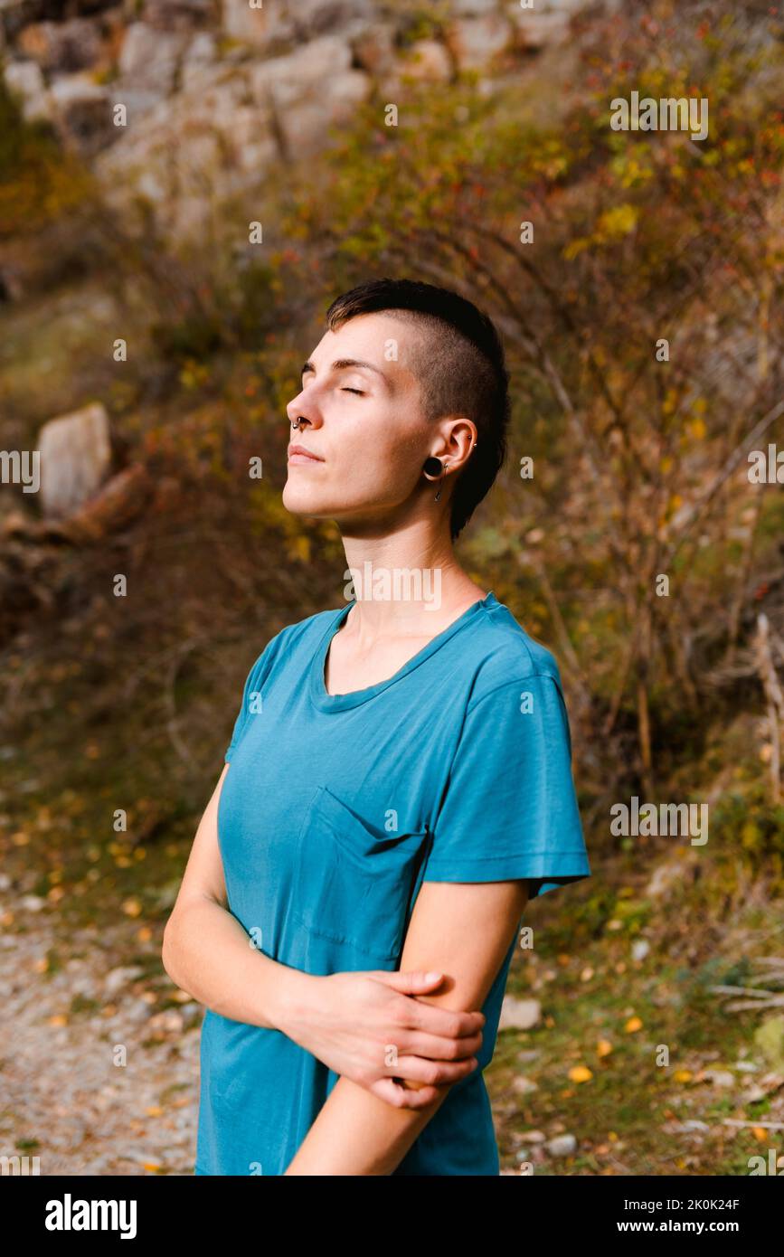 Side view of calm young lady in casual wear with closed eyes breathing ...