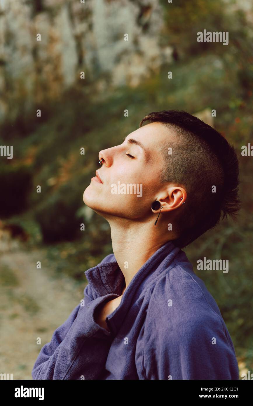 Side view of calm young lady in casual wear with closed eyes breathing ...