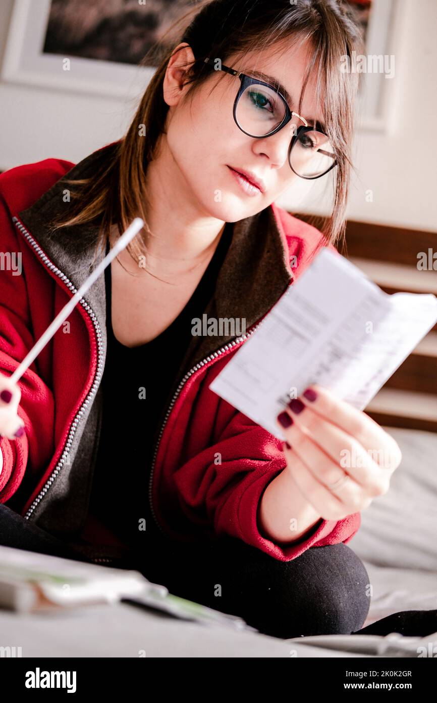 Focused female in eyeglasses with pipette reading instruction leaflet ...