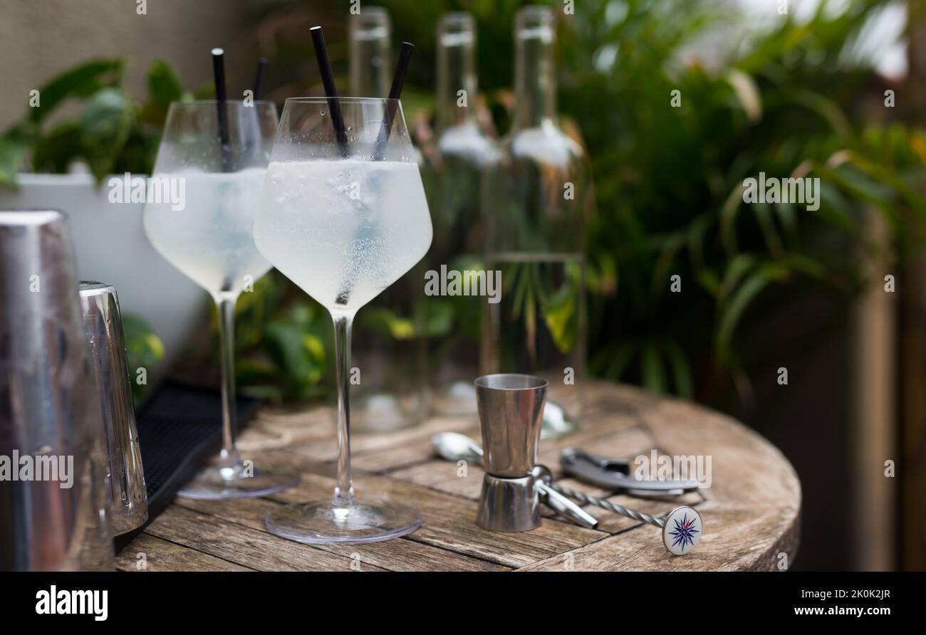 transparent cocktail with two straws in a glass with a stem on a wooden ...