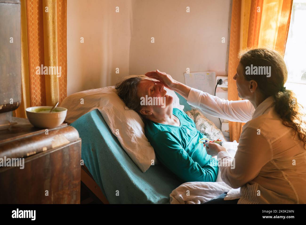 Side view of female nurse feeding paralyzed elderly lady with puree ...