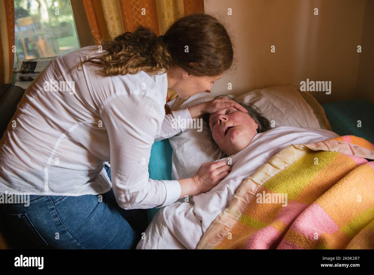 Kind female nurse touching face of woman with disability while taking ...