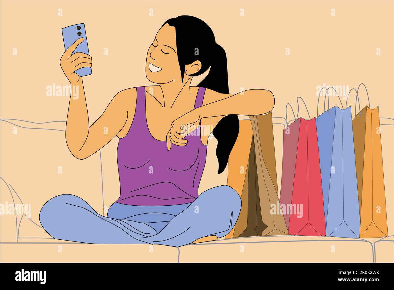 A young woman sitting on a sofa with shopping bags and shopping online ...