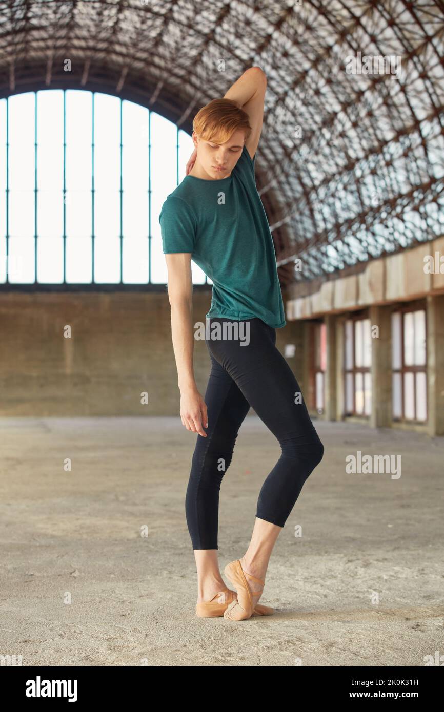 Side view of flexible young ballet dancer in leotard stretching while ...