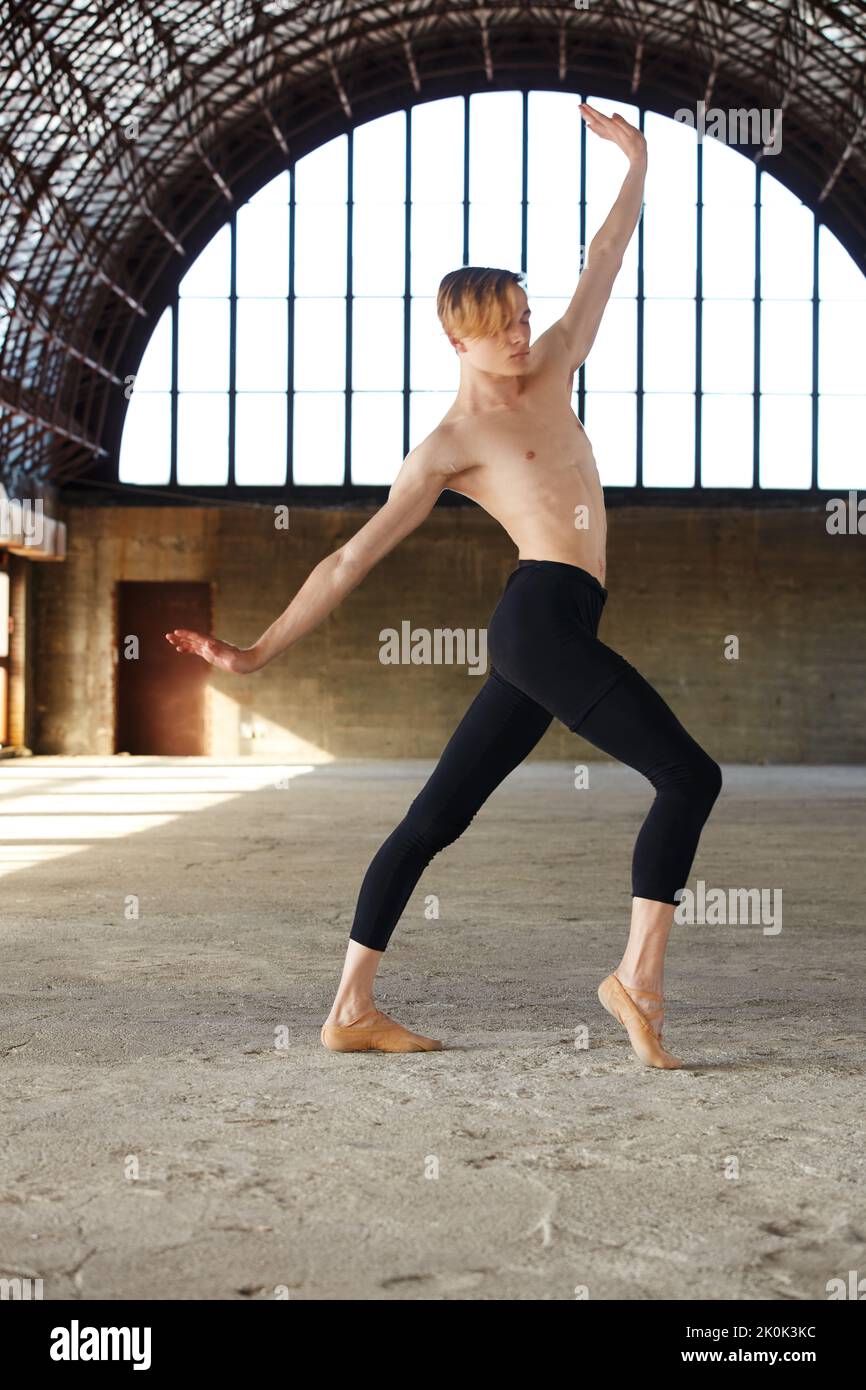 Side view of flexible young ballet dancer in leotard stretching while ...